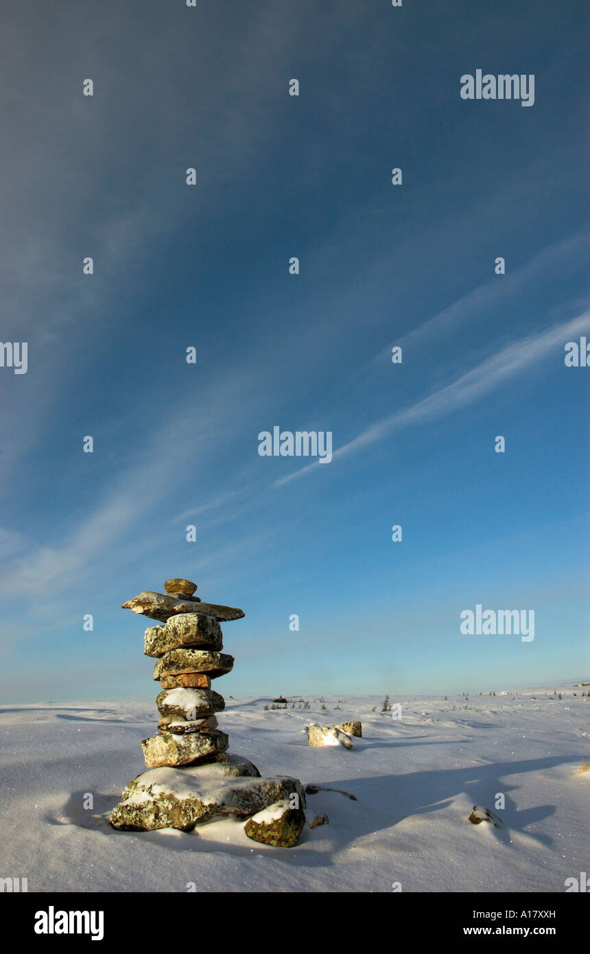High cloud behind an inukshuk surrounded by deep snow in the Canadian ...