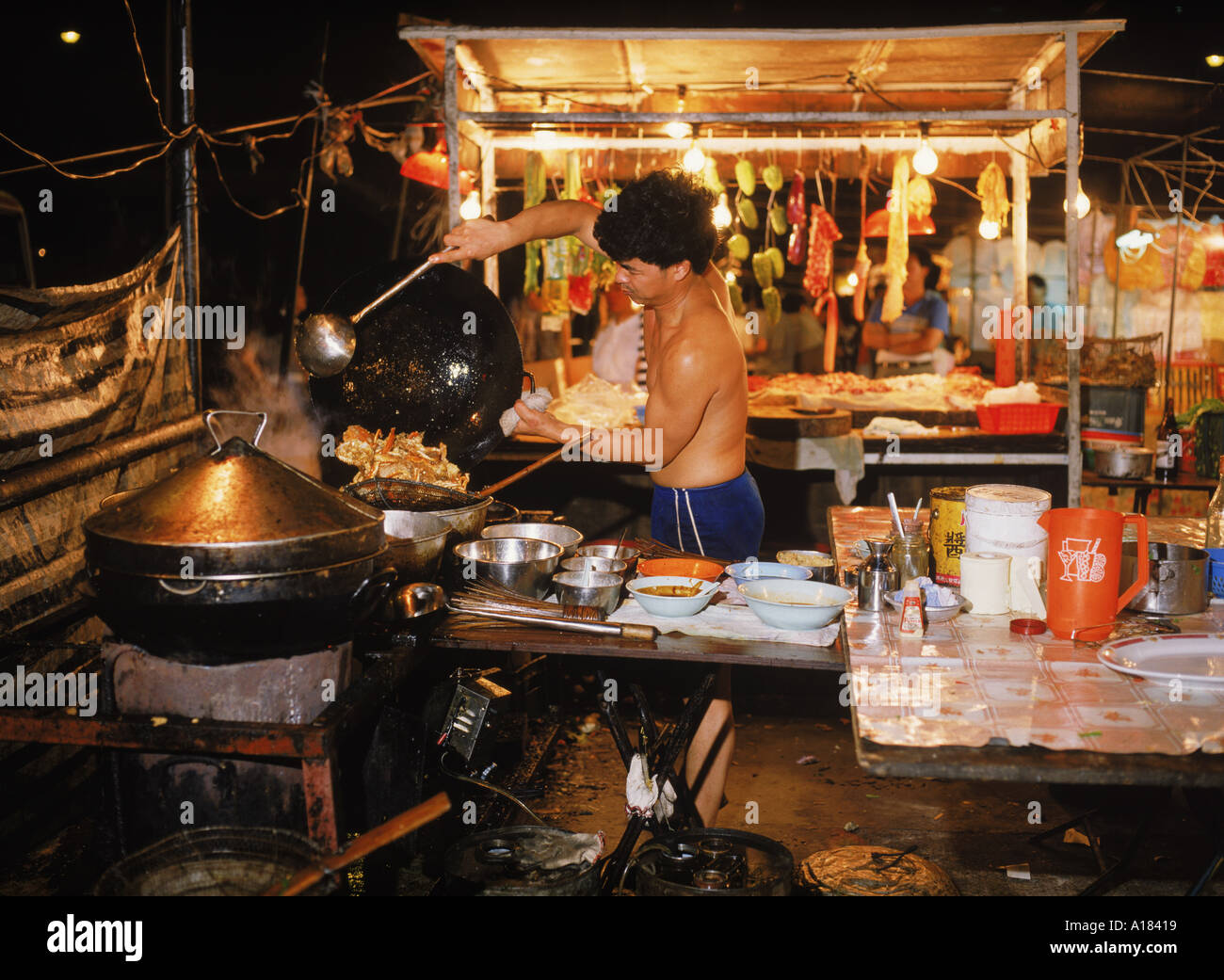 Man emptying a wok in a kitchen in the Poor Mans Nightclub an open air ...