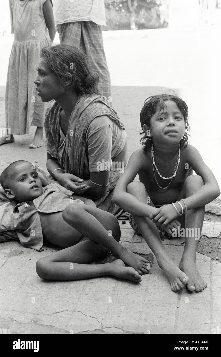 B/W of a woman and two children who are street dwellers begging on the ...