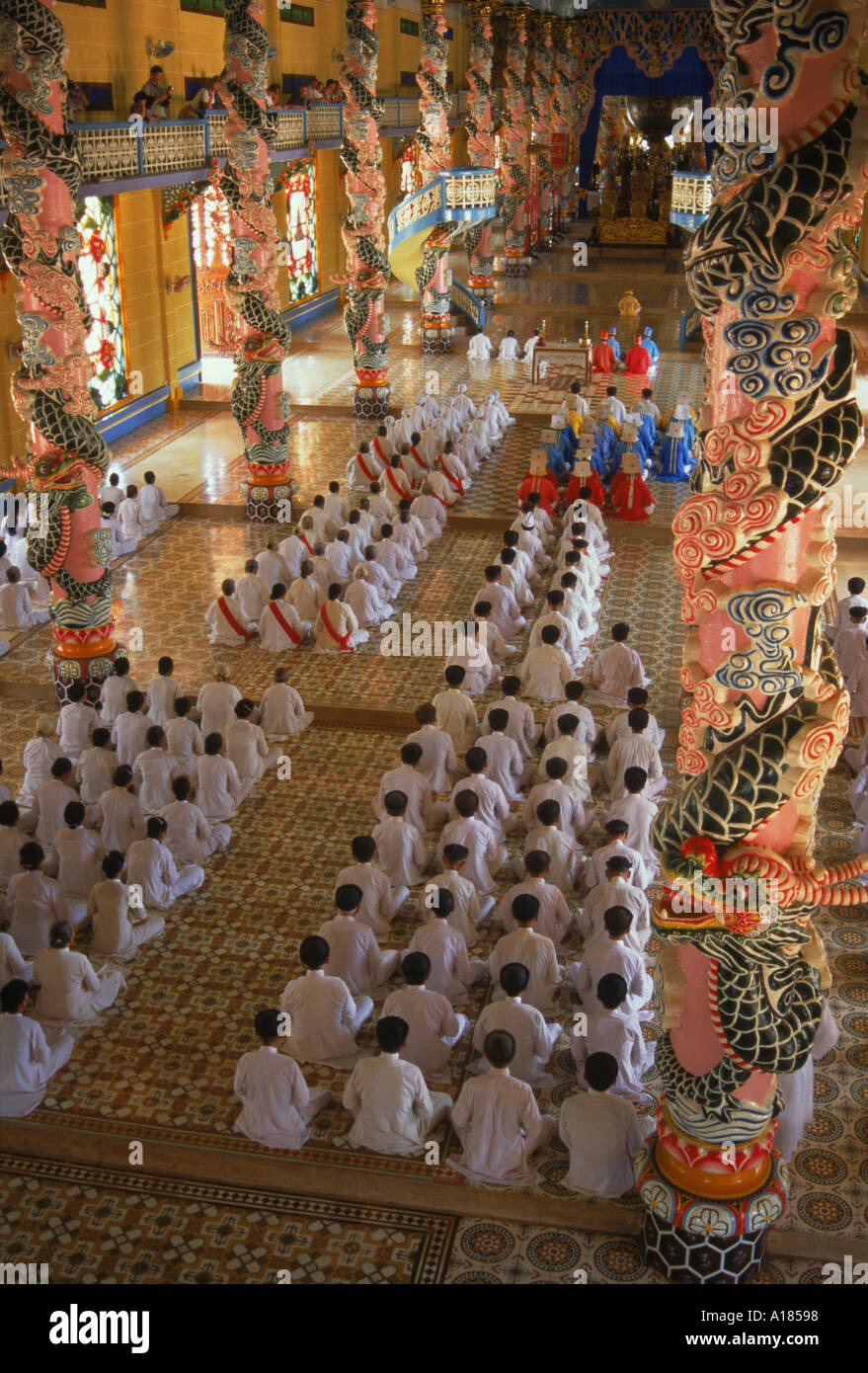 Rows of monks at prayer inside a temple of the Caodai religious sect at ...
