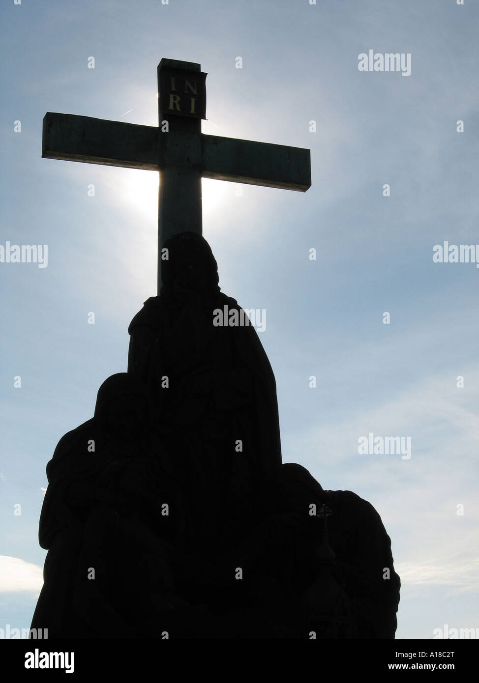 A cross with INRI is backlit against a bright blue sky Stock Photo - Alamy