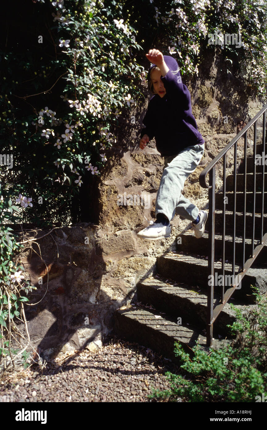 Girl aged 7 jumping down a flight of stone steps in a garden Stock ...