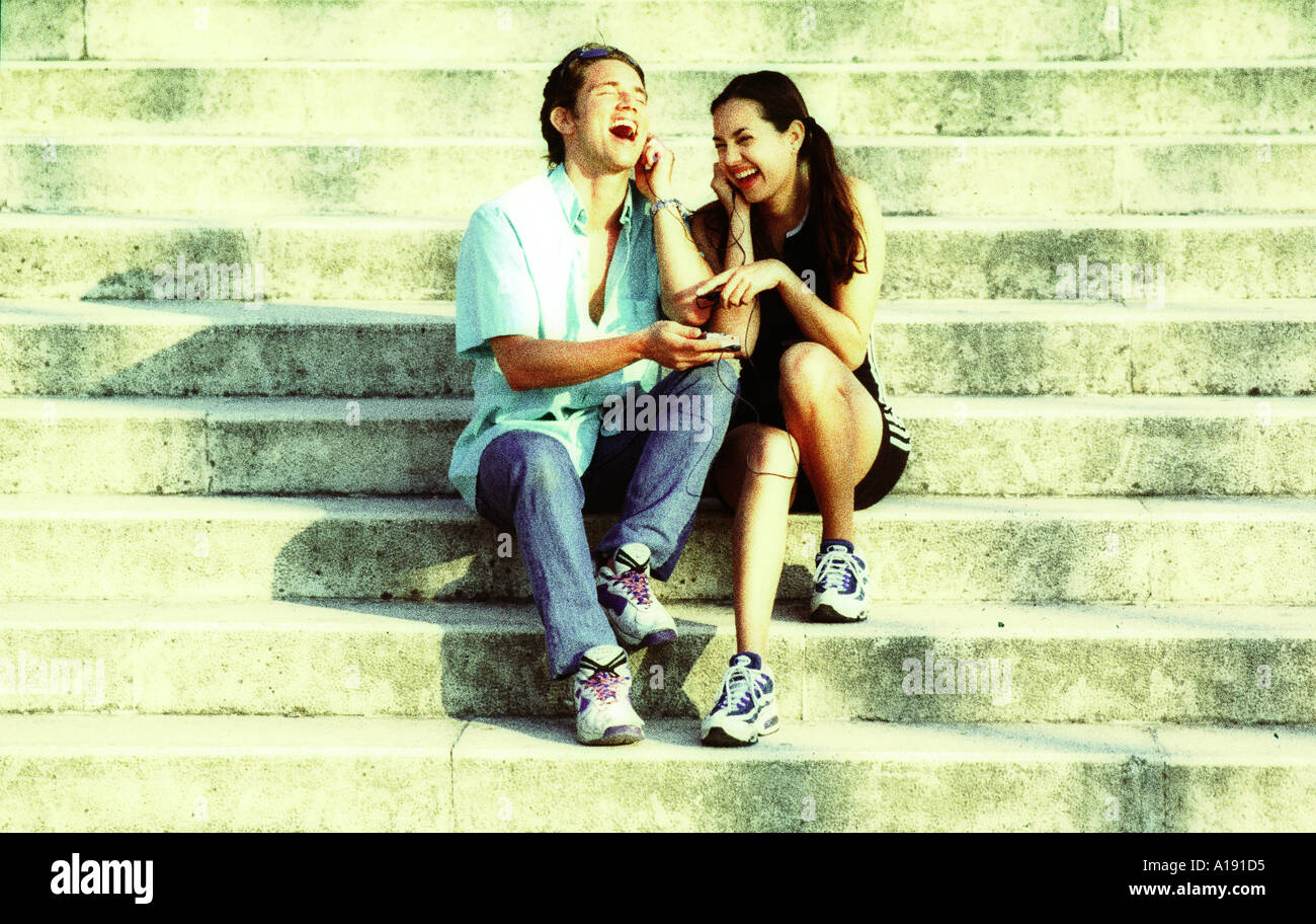 couple sitting on steps listening to walkman Stock Photo - Alamy