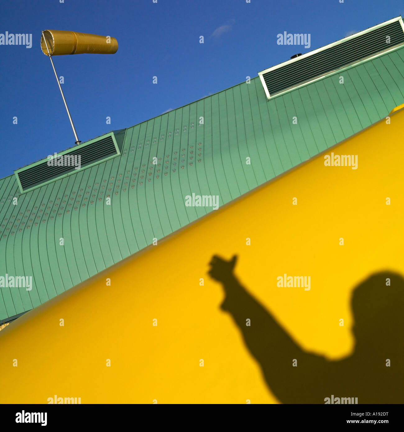 Windsock on top of a roof against blue sky with a male shadow in the ...