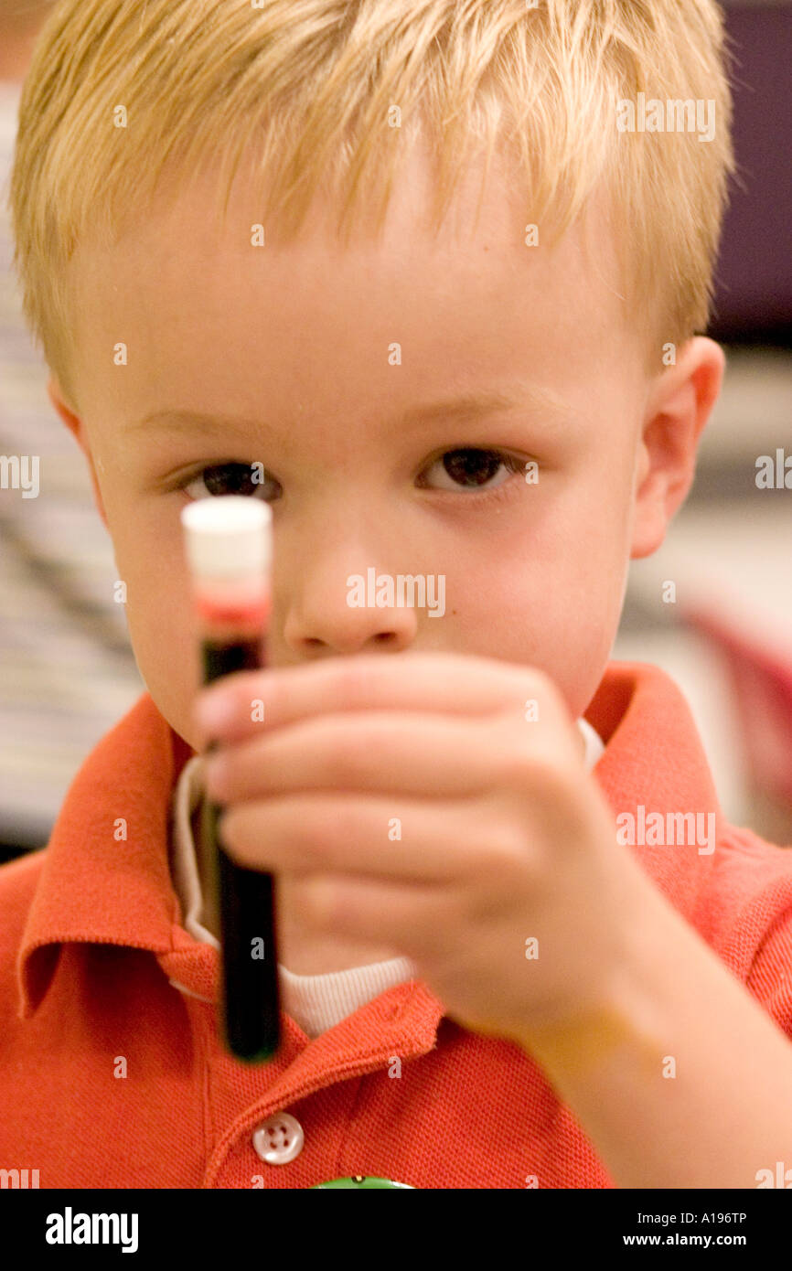 Young scientist studying tube of red material at the Science Museum. St ...