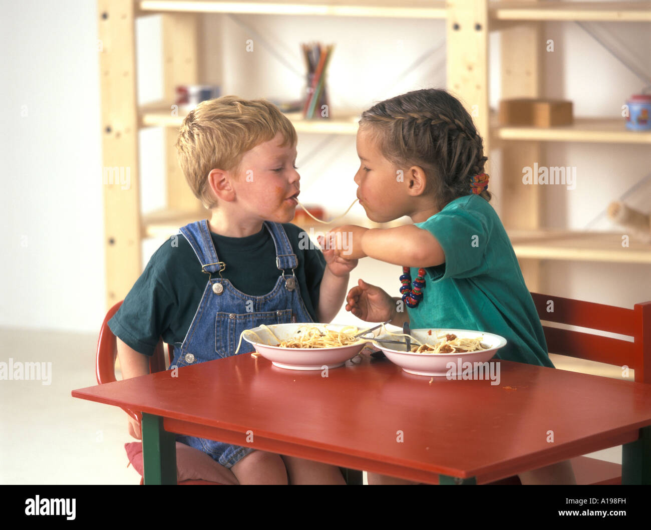 Boy and girl eating spaghetti together Stock Photo - Alamy