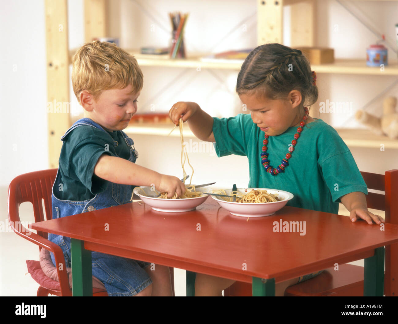 Boy and girl eating spaghetti together Stock Photo - Alamy