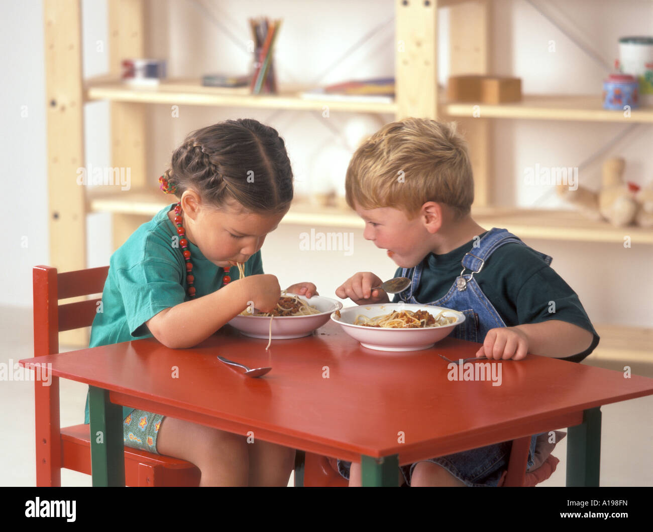 Boy and girl eating spaghetti together Stock Photo - Alamy