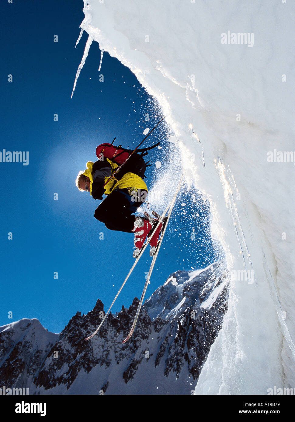 Male skier jumping off cornice with sun and mountains behind Stock ...