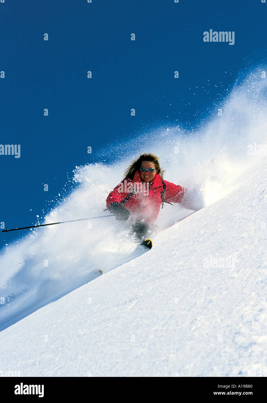 Female action skier turning through deep powder Stock Photo - Alamy