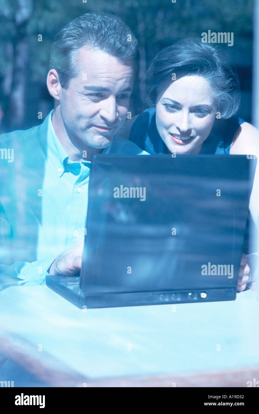 Business partners working on laptop through window Stock Photo - Alamy