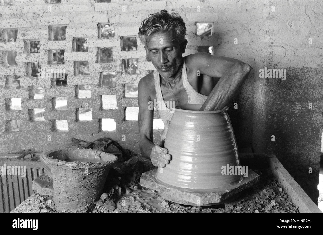 B/W of a potter turning a pot on a treadle wheel in rural Tamil Nadu ...
