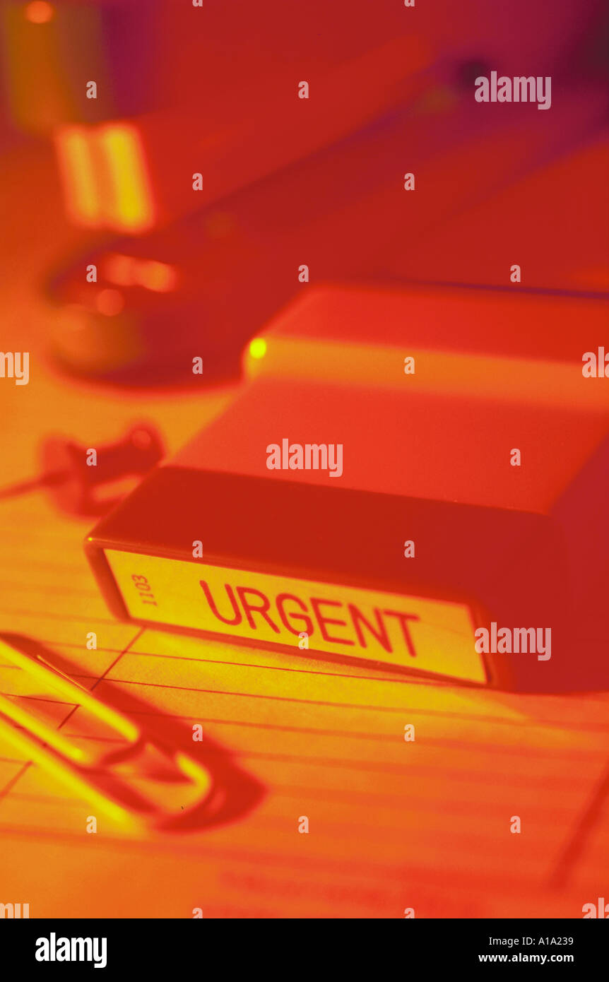 Still life of an urgent stamp a stapler a push pin and a paper clip The ...