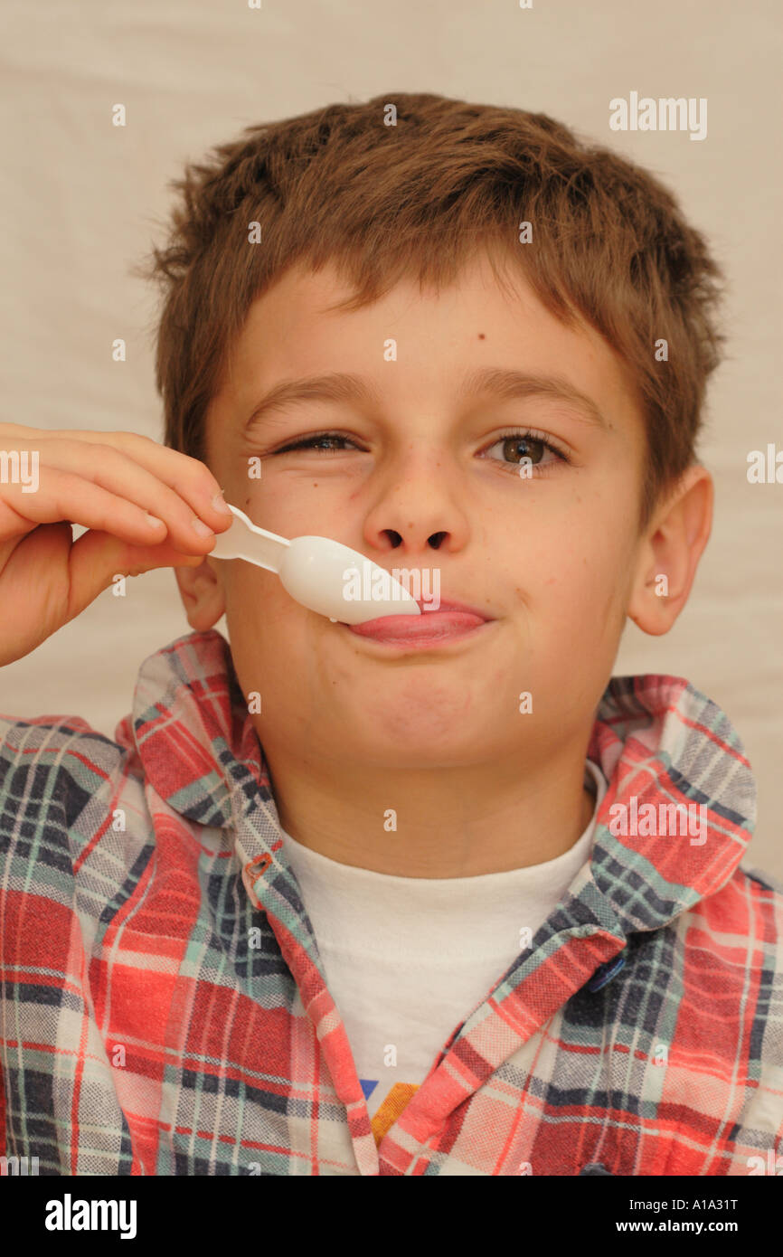 Young boy child feeling ill taking a spoon full of medicine with bitter ...