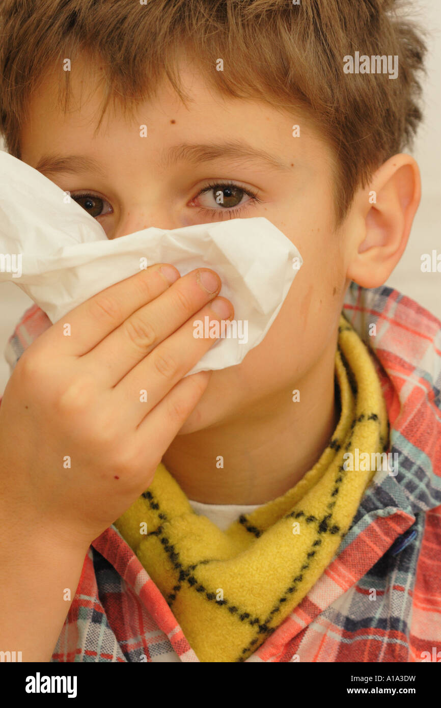 Young boy feeling ill unwell with cold flue wiping nose with ...