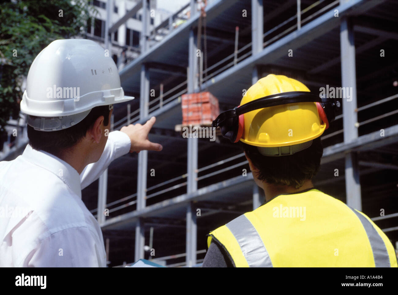 Architect with construction worker looking up at building site Stock ...