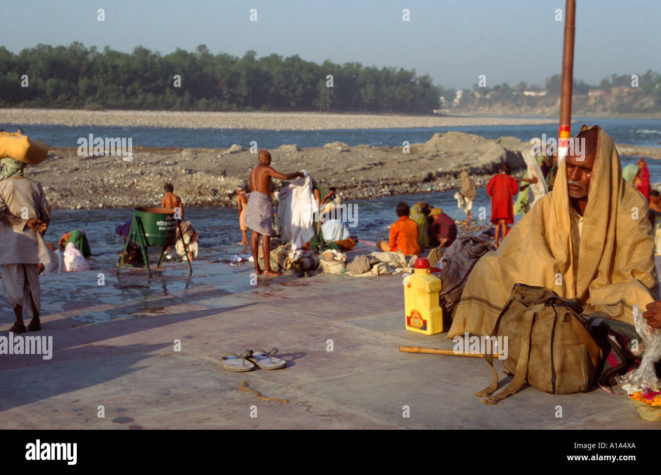 Pilgrim on the steps of Triveni Ghat with the River Ganges behind ...