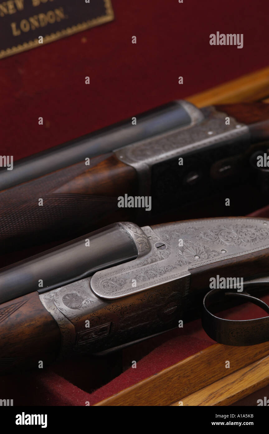 Two vintage side by side shotguns sitting on a red felt lined gun box ...