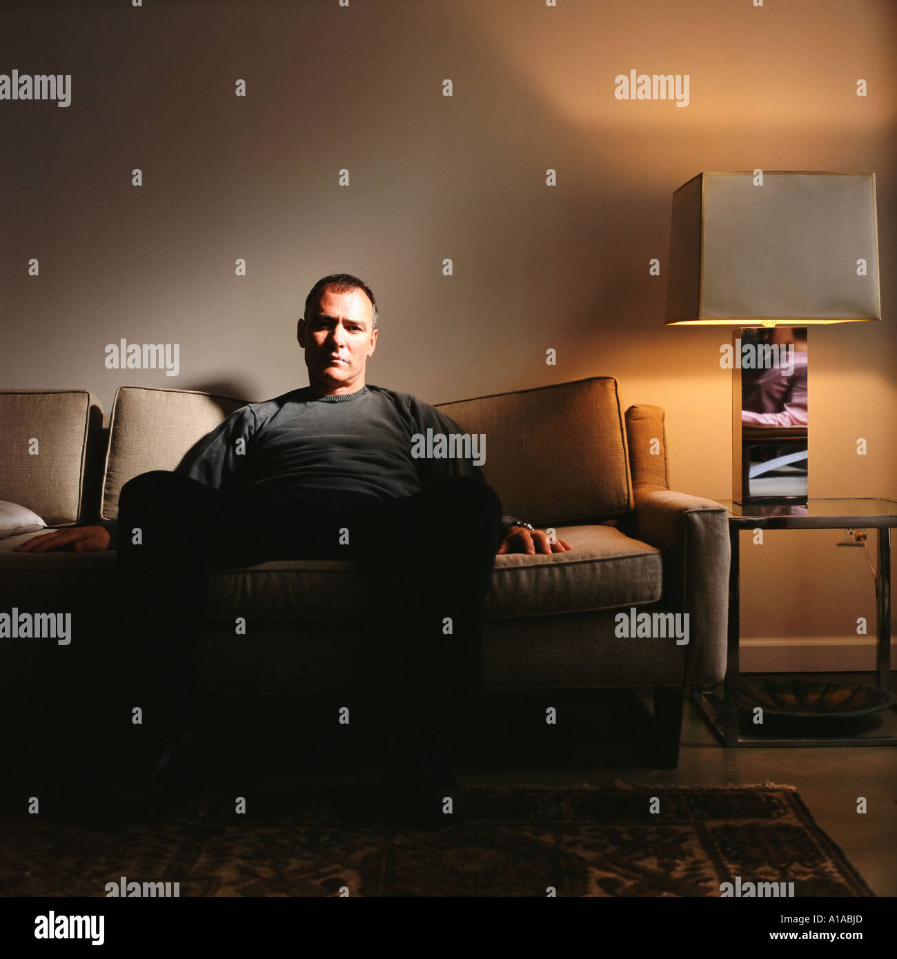 Man sitting on sofa Stock Photo - Alamy