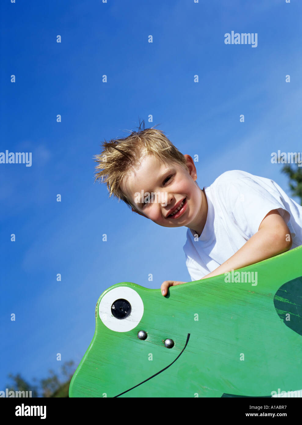 Happy boy riding wooden frog Stock Photo - Alamy