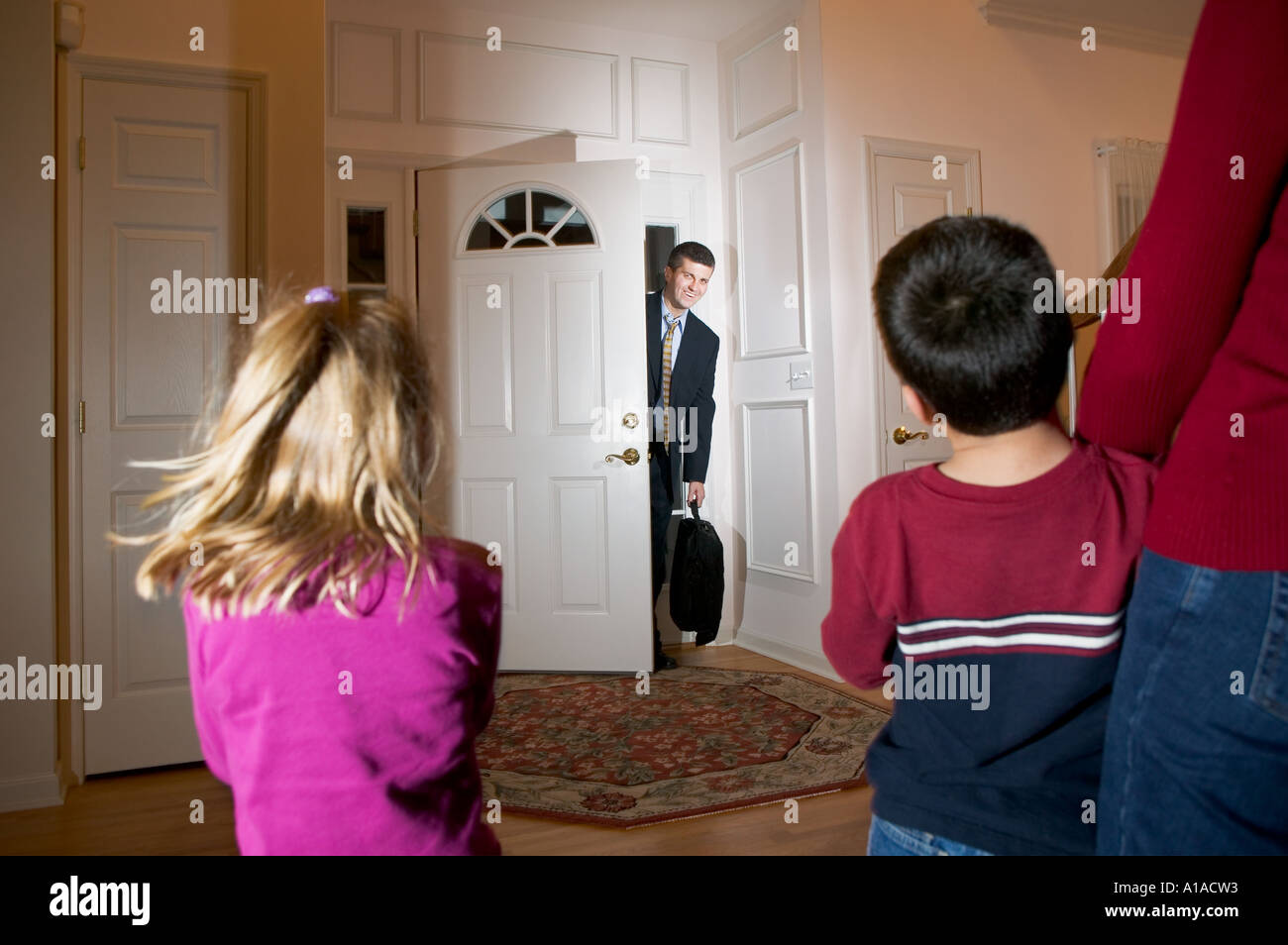 Family greeting businessman as he arrives home Stock Photo - Alamy