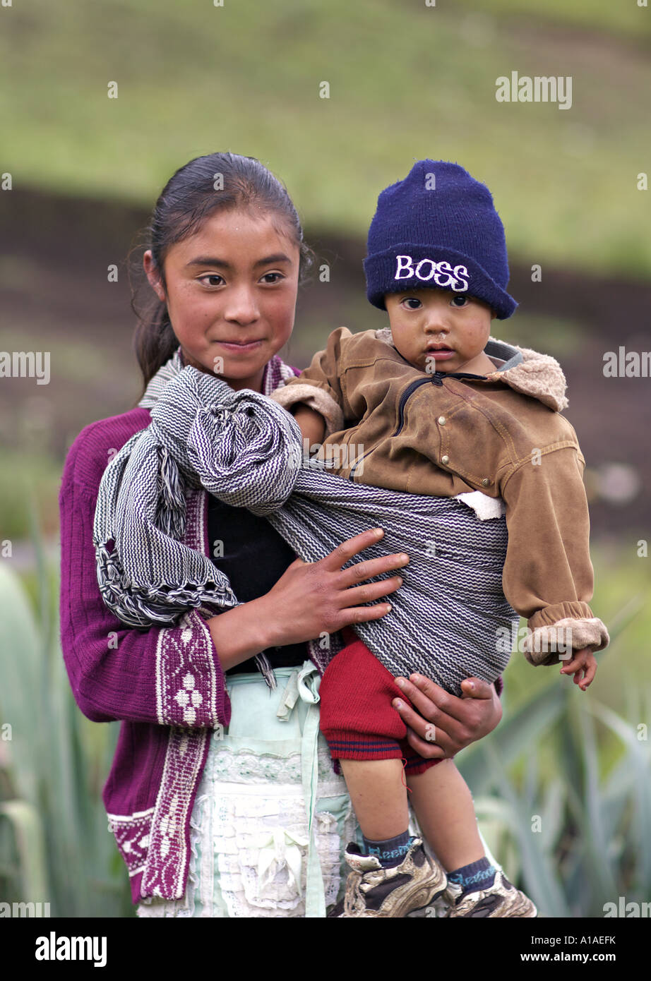 GUATEMALA CAPELLANIA Young indigenous Maya Ixil girl carrying her baby ...