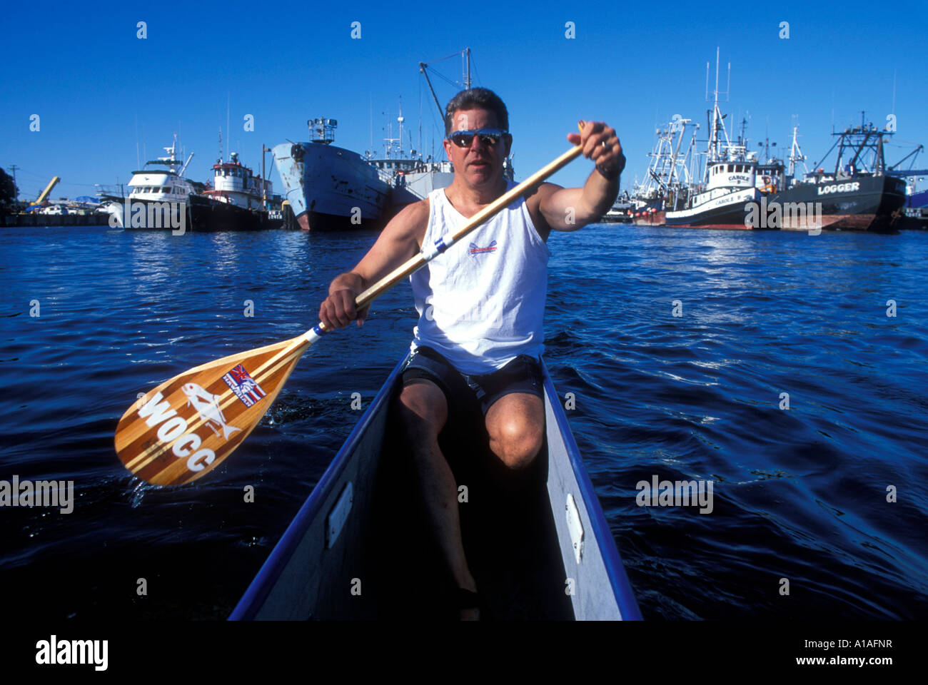 USA Washington Seattle Steve Beaudry paddles outrigger canoe by fishing boats at Fishermans Fall ...