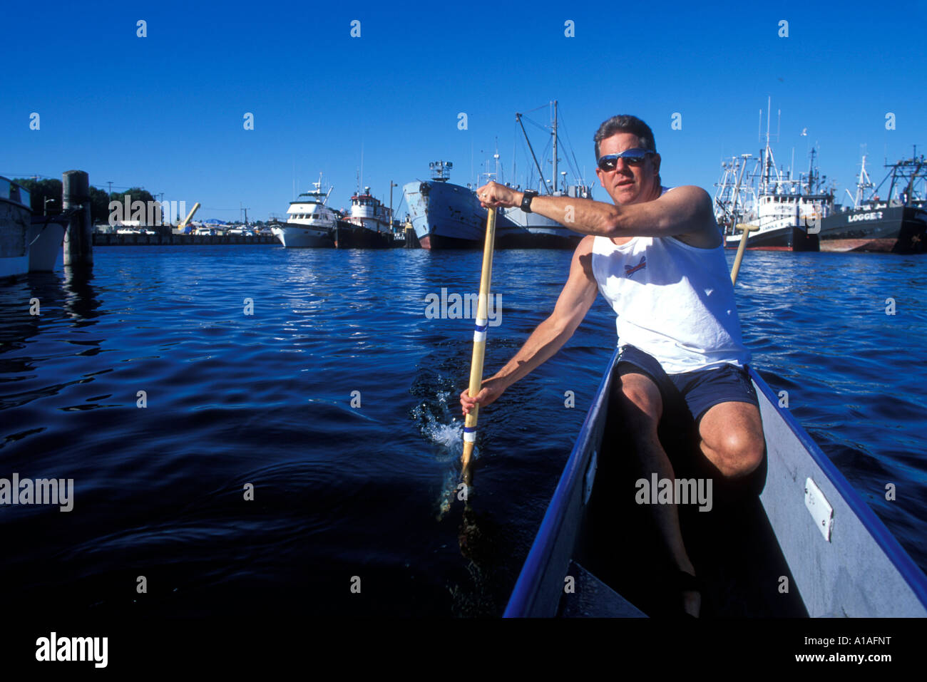 USA Washington Seattle Steve Beaudry paddles outrigger canoe by fishing boats at Fishermans Fall ...