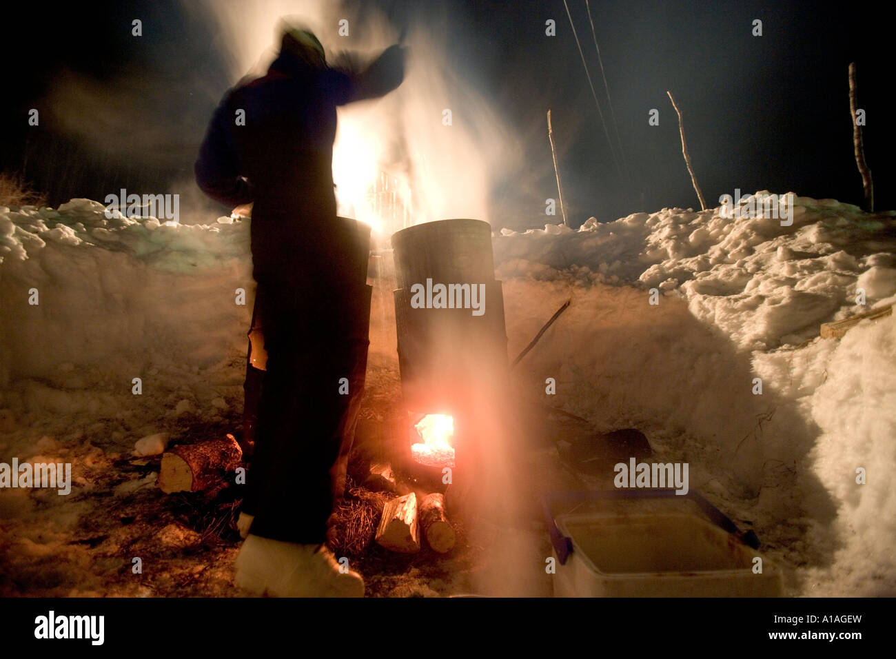 USA Alaska Takotna Musher is shrouded in steam while ladling hot water ...