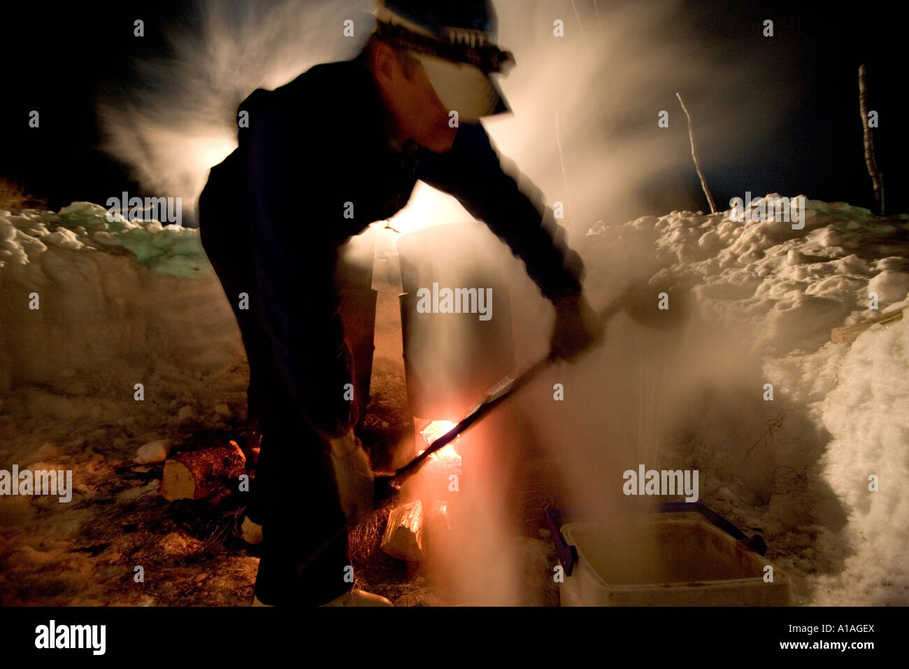 USA Alaska Takotna Musher is shrouded in steam while ladling hot water ...