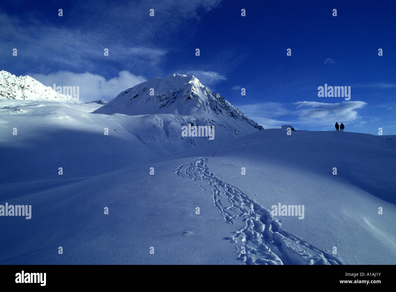 USA Alaska Chugach State Park Climbers hike through deep snow at summit ...