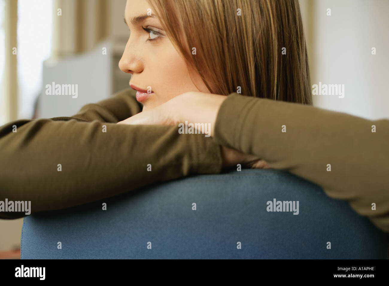 Young woman resting on back of chair Stock Photo - Alamy
