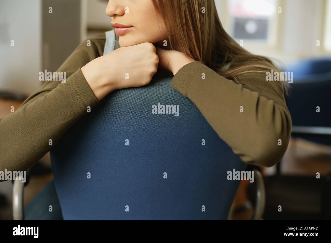 Young woman resting on back of chair Stock Photo - Alamy
