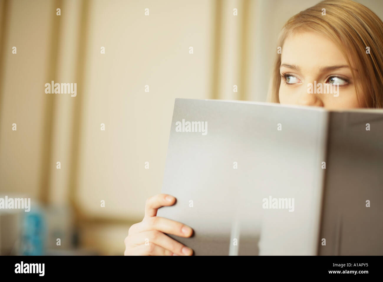 Woman peering over top of folder Stock Photo - Alamy