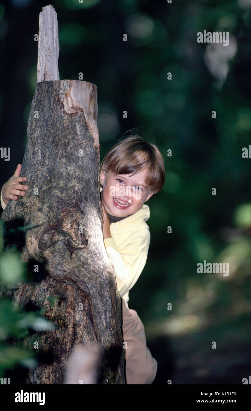 boy peeking from behind tree youthfulness Stock Photo - Alamy