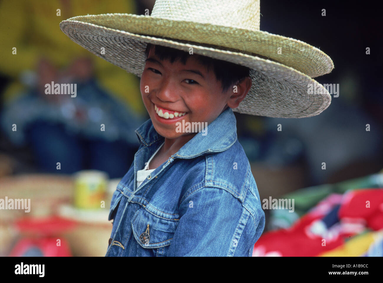 Portrait of a smiling boy wearing a denim jacket and two straw hats in ...