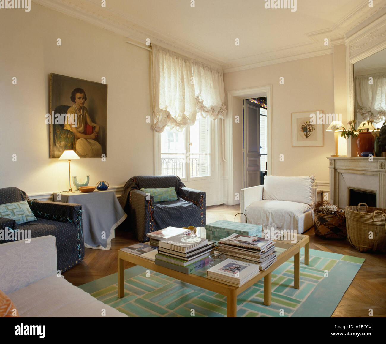 Lighted lamps in livingroom,festoon blinds at window. Table with books ...