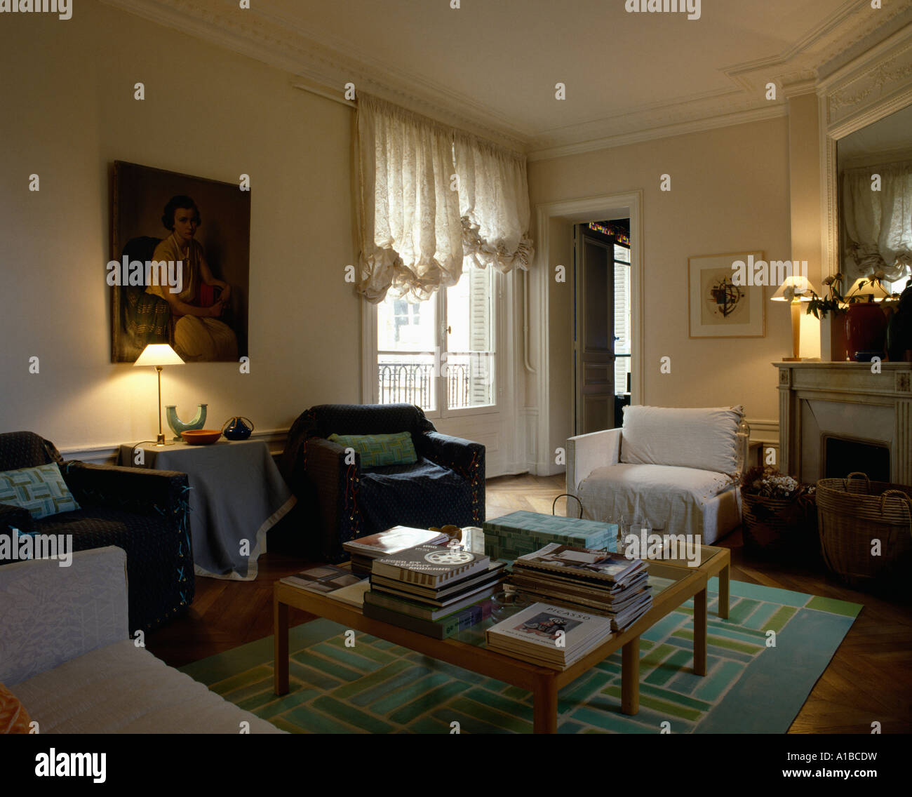 Lighted lamps in livingroom with festoon blinds at tall window and pile ...
