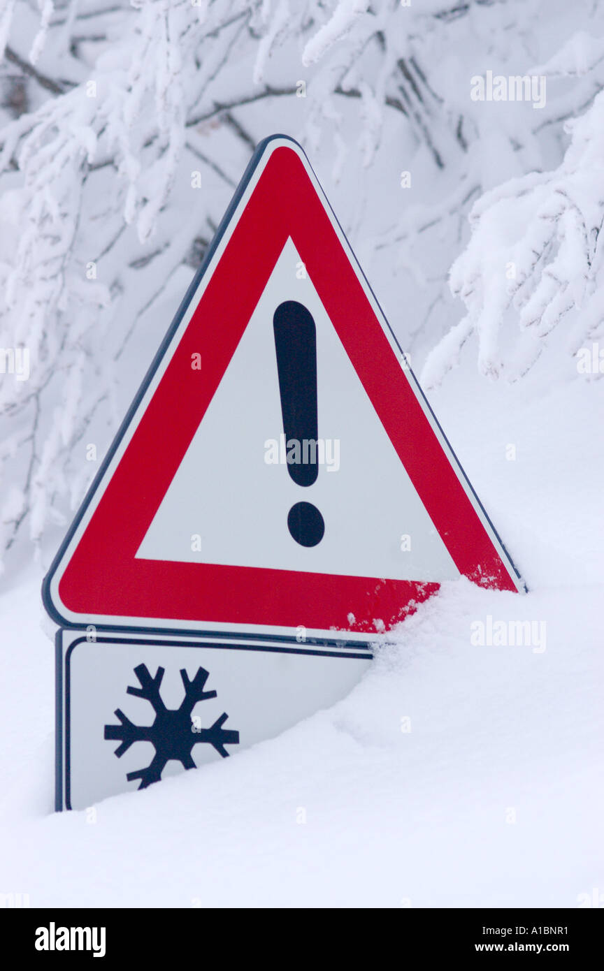 Road sign with an exclamation mark in a red triangle, snow covered ...