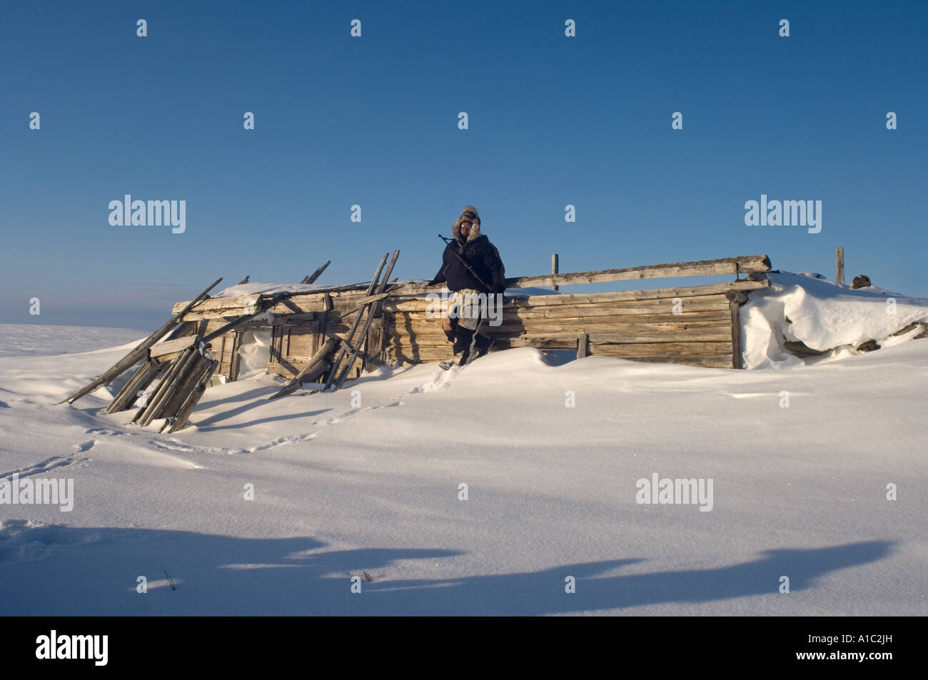 Inupiat guide in front of an old cabin on the Mackenzie river delta ...