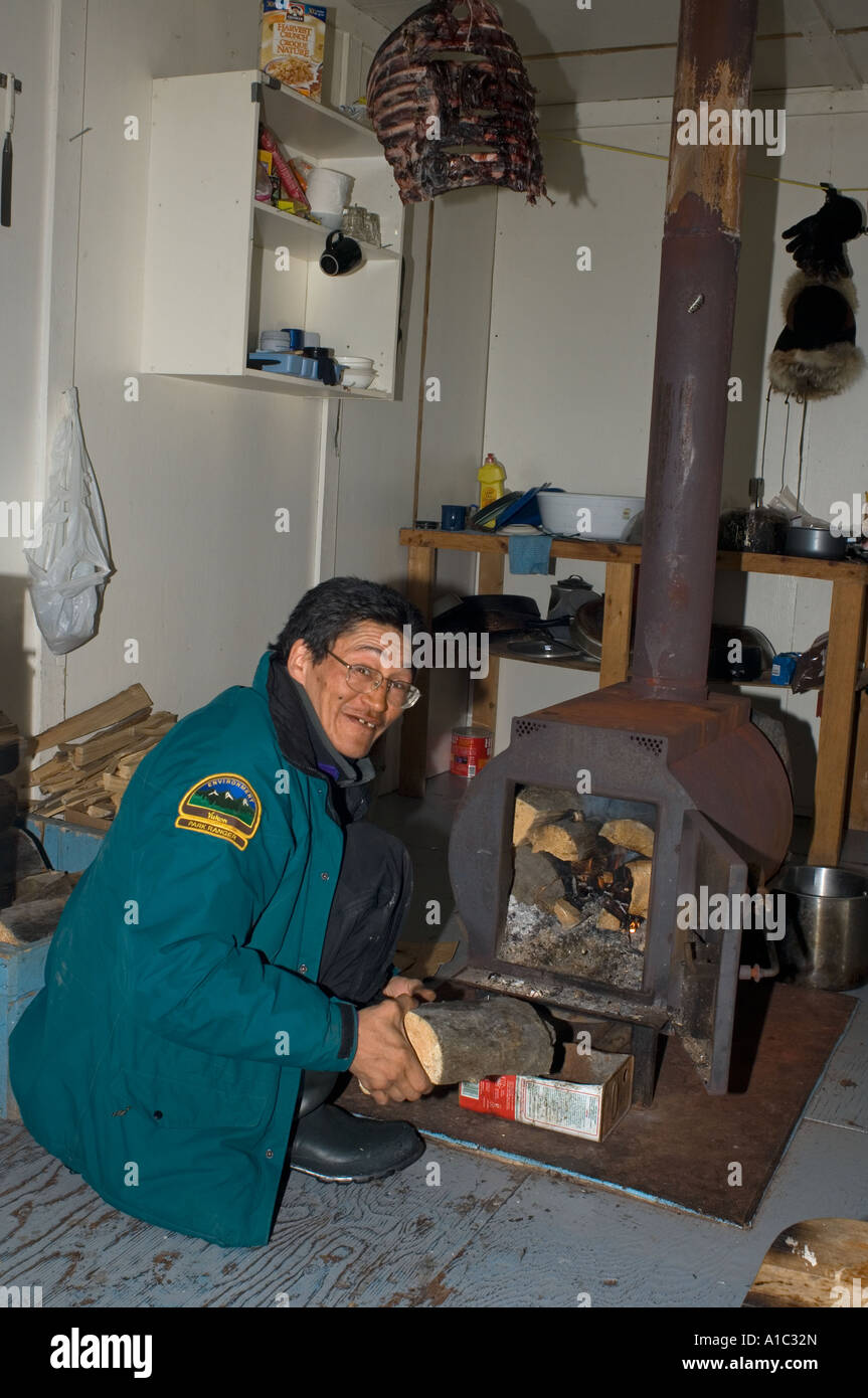 Inupiat man builds a fire in the hunters and trappers cabin on Herschel ...