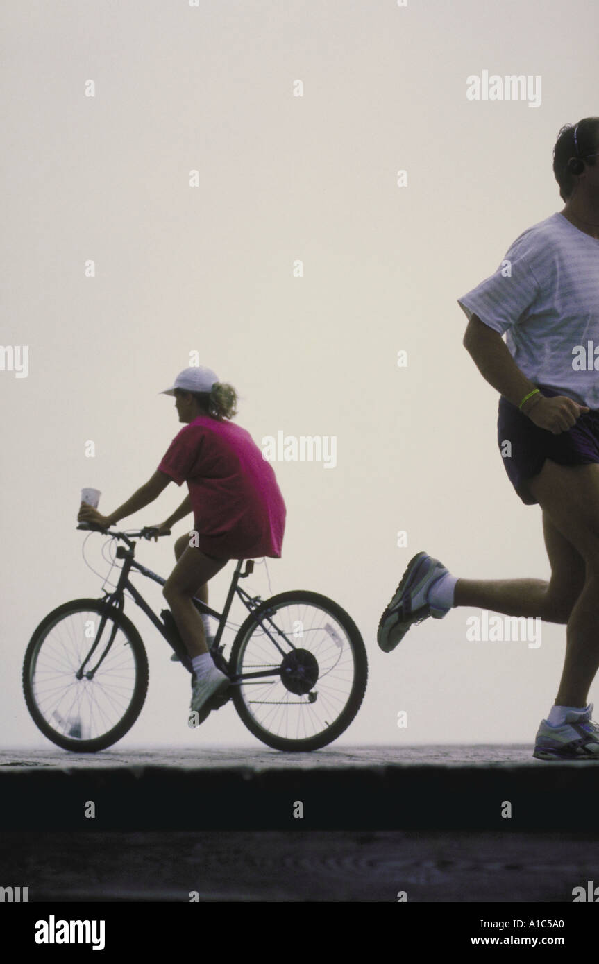 Woman riding bicycle and jogger on boardwalk at beach Stock Photo - Alamy
