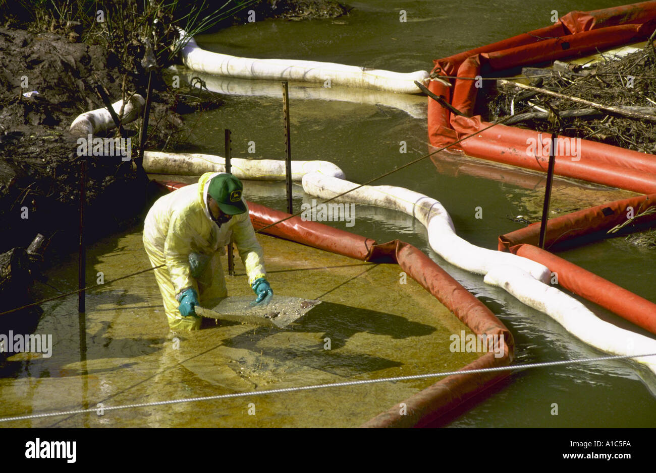 Environmental worker uses screen to remove oil and debris from a ...