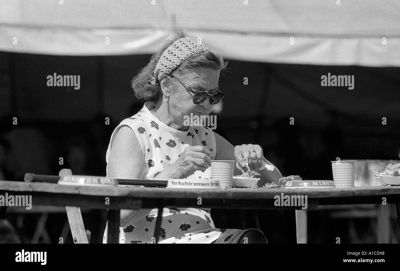 Old lady eating fish and chips at an outdoor table at a show Stock ...