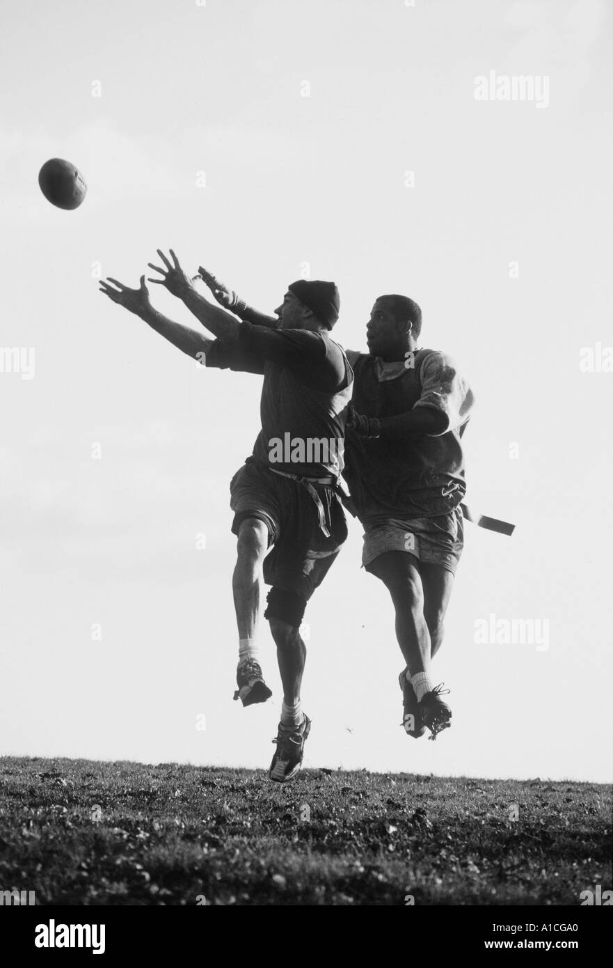 Two touch football players leap and jostle for position while trying to ...