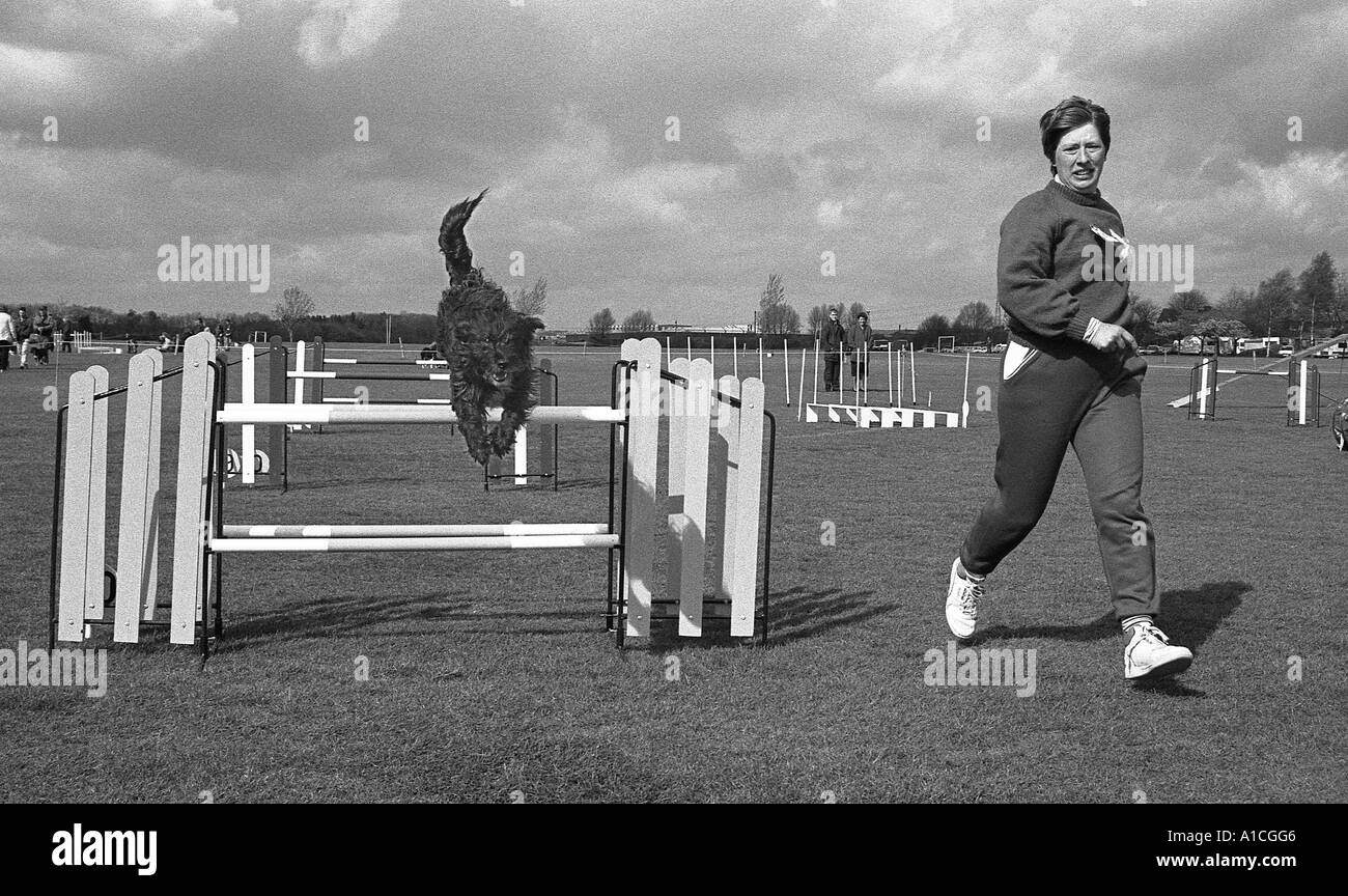 Person running with their dog as it clears a fence at a dog agility ...