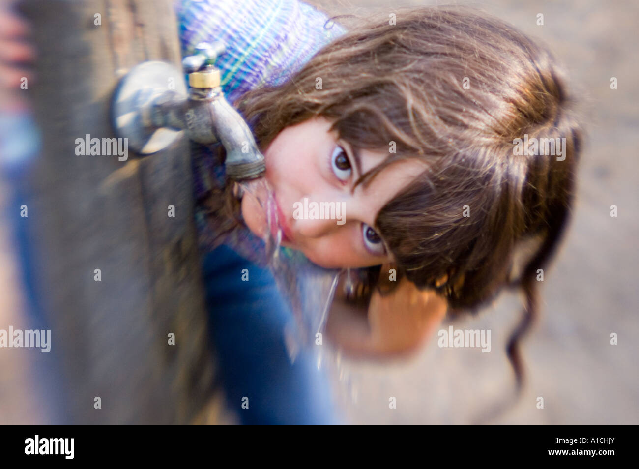 A young girl drinking from an outdoor faucet Stock Photo - Alamy