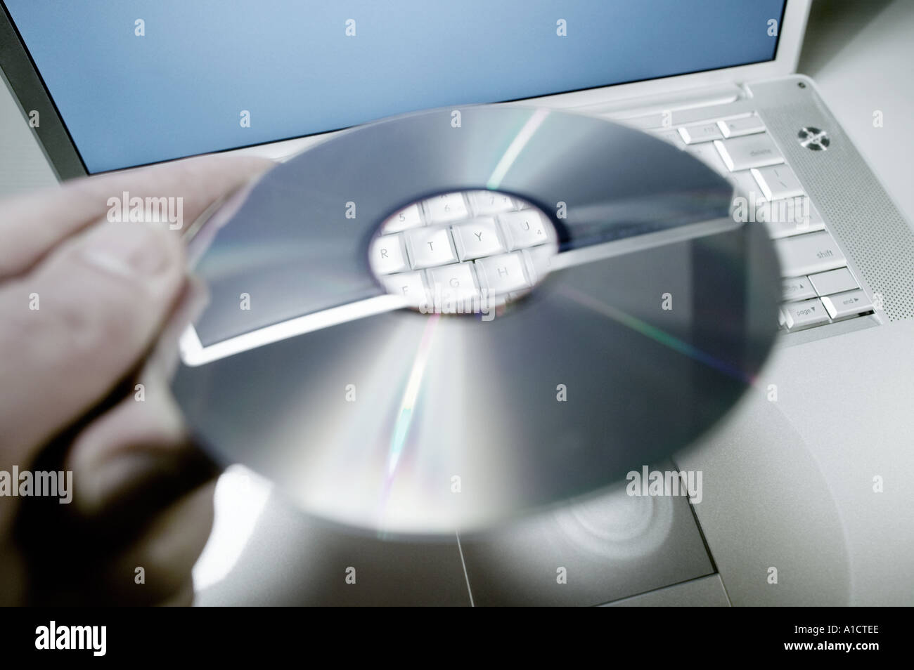 Hand holding CD above laptop computer Stock Photo - Alamy