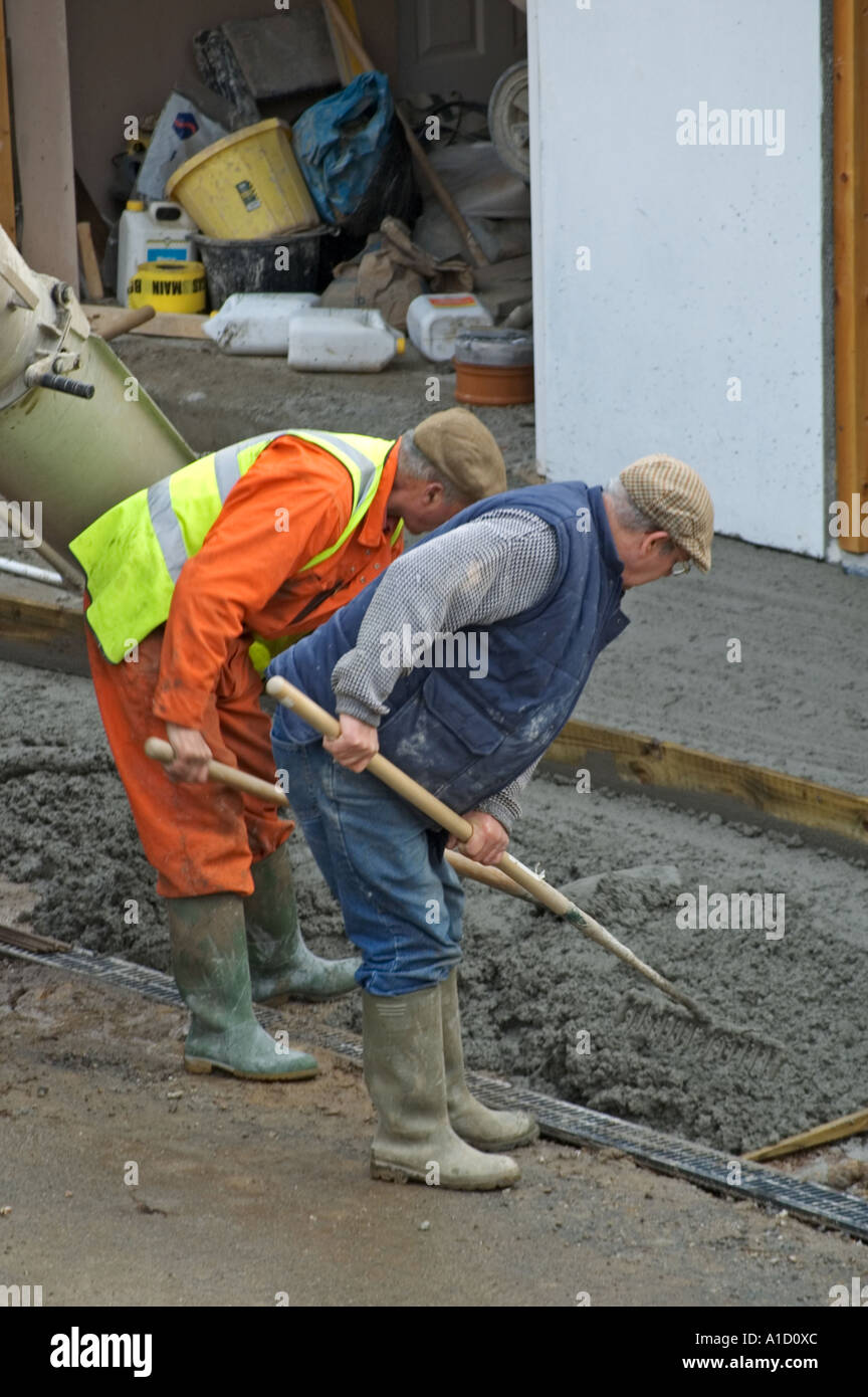 two construction workers spreading cement Stock Photo - Alamy