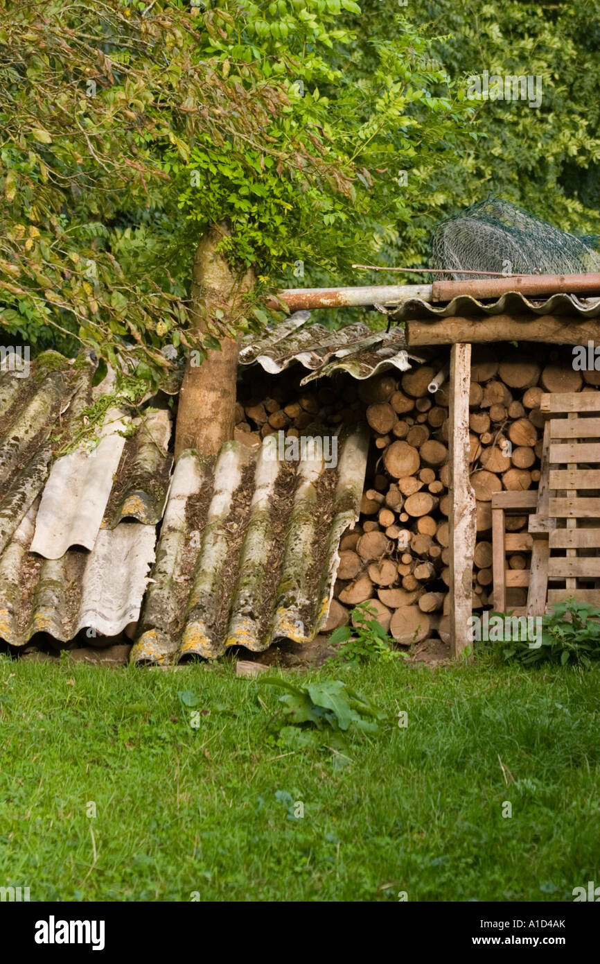 Large stack of logs for fuel stored under a makeshift shed of timber ...